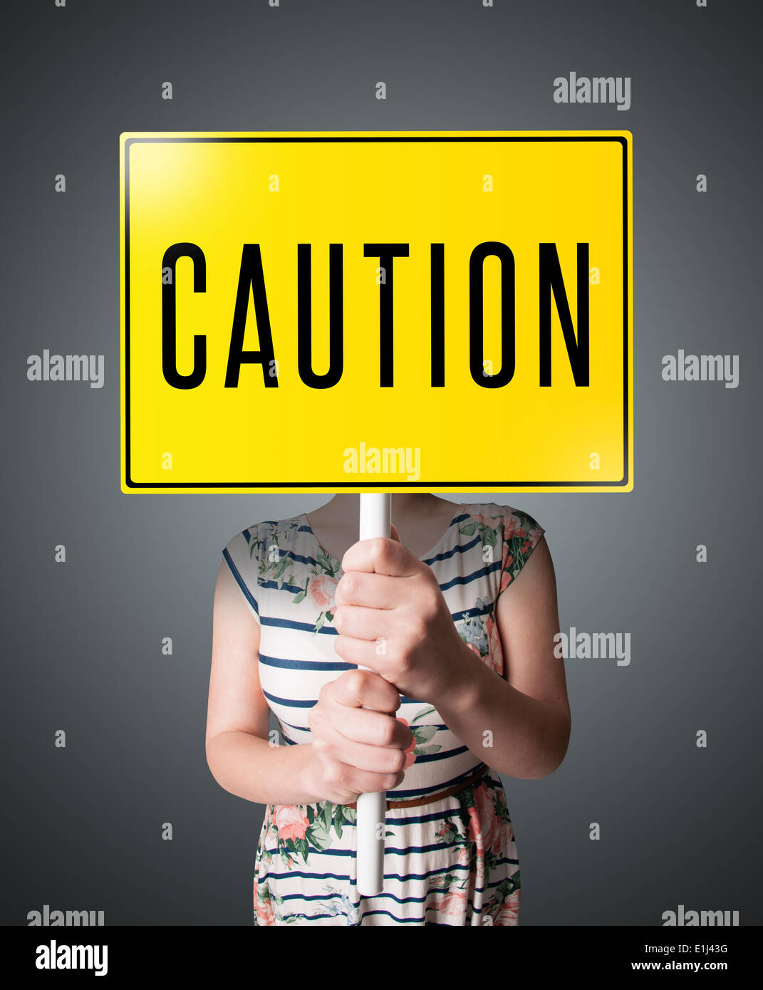 Young woman holding a caution sign Stock Photo - Alamy