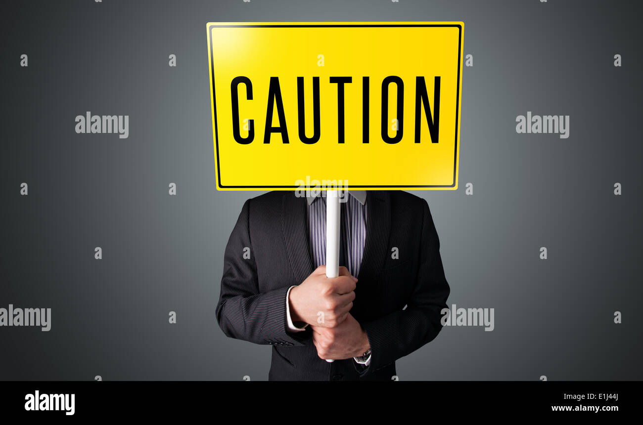 Businessman holding a caution sign Stock Photo - Alamy