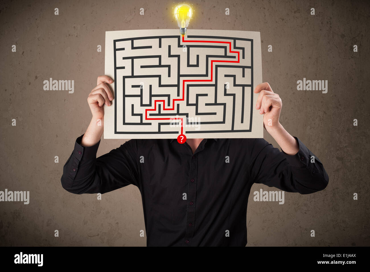 Businessman holding a paper with a labyrinth on it in front of his head ...