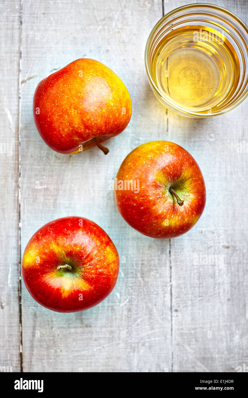 Three apples and a glass of apple juice on grey wood, elevated view ...