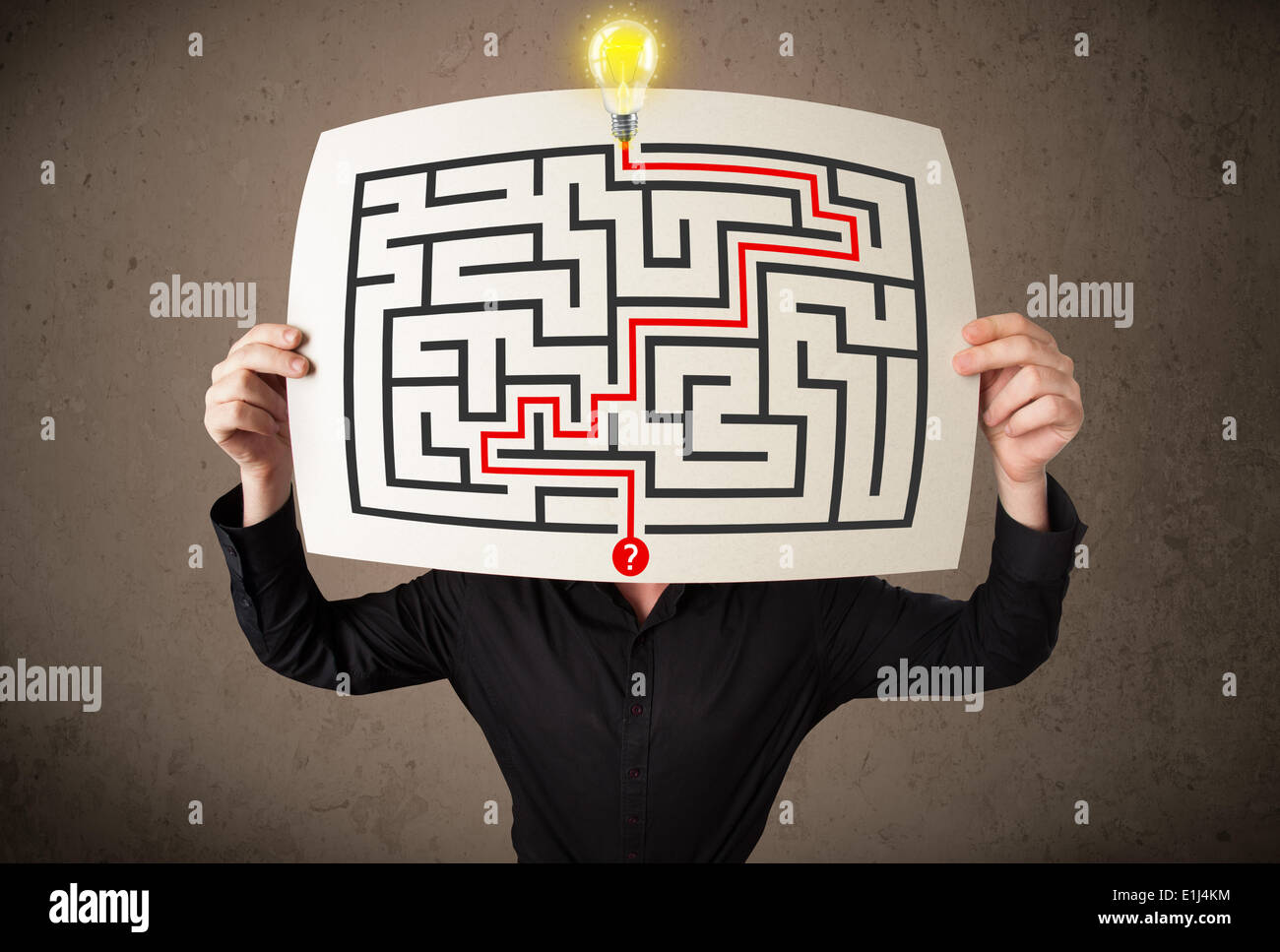 Businessman holding a paper with a labyrinth on it in front of his head ...
