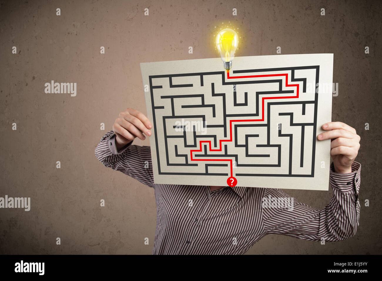 Businessman holding a paper with a labyrinth on it in front of his head ...