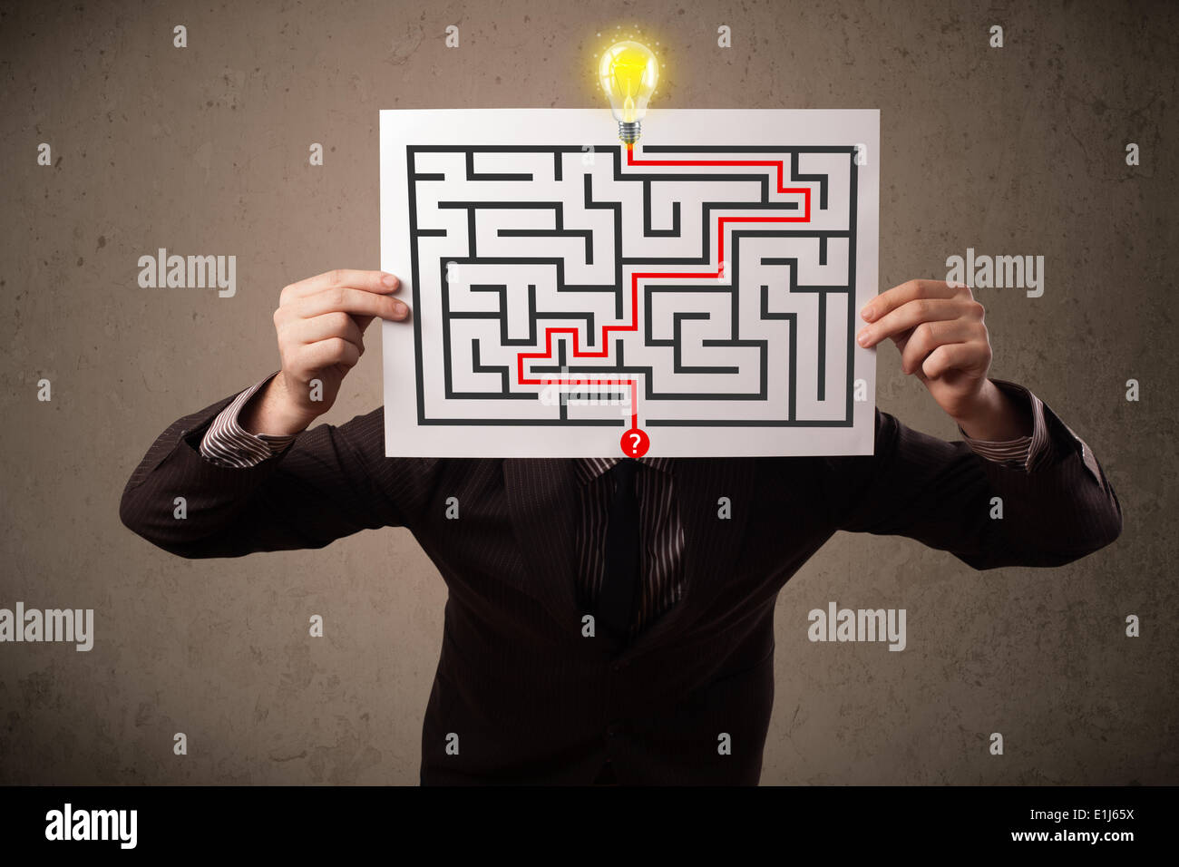 Businessman holding a paper with a labyrinth on it in front of his head ...
