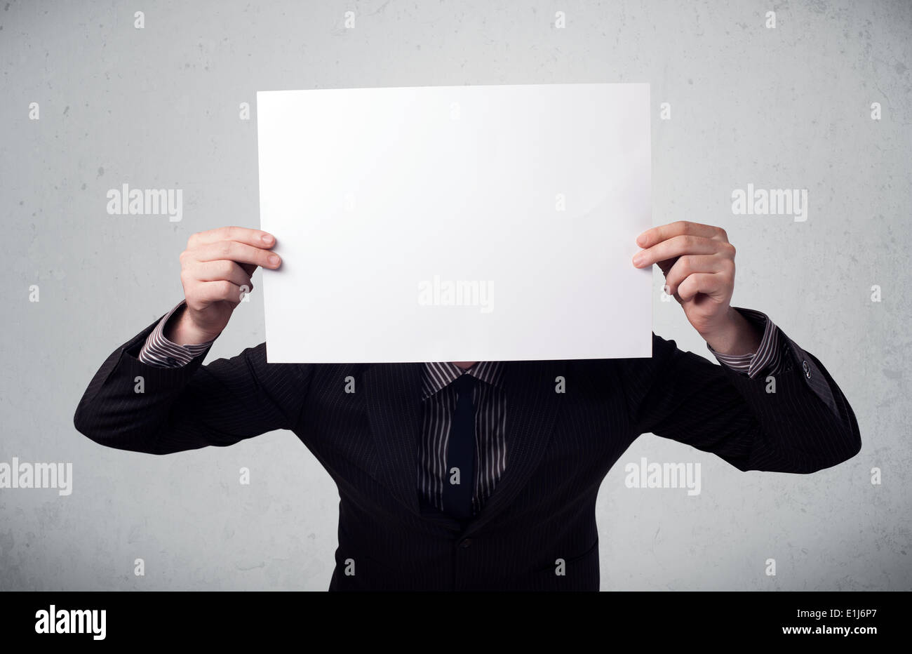 Businessman holding in front of his head a paper with copy space Stock ...