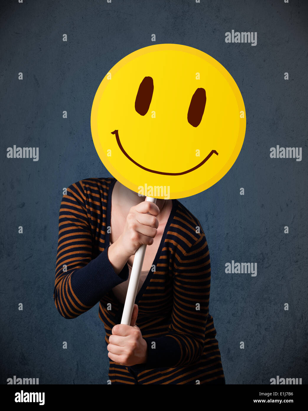 Young woman holding a smiley face emoticon Stock Photo - Alamy