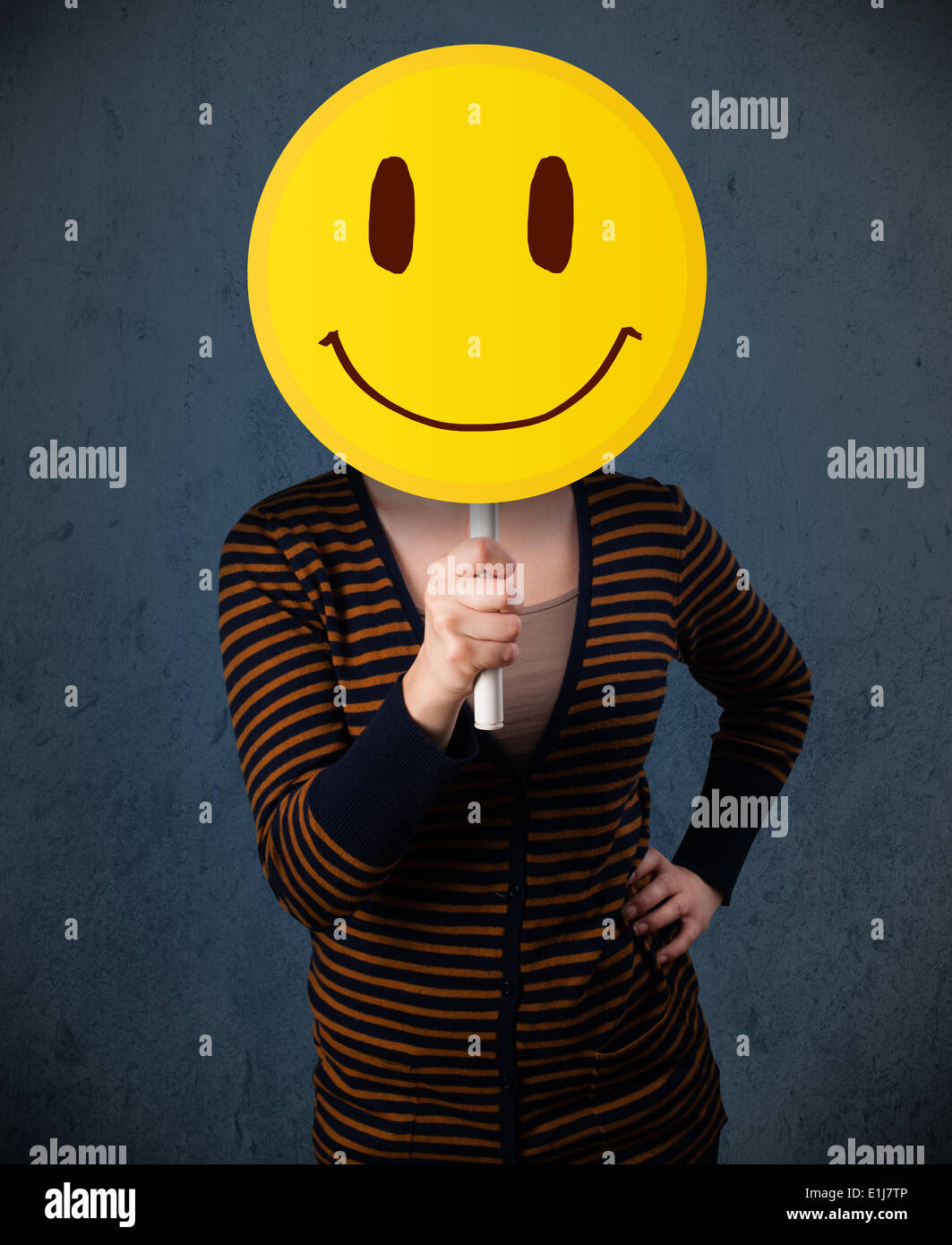 Young woman holding a smiley face emoticon Stock Photo - Alamy