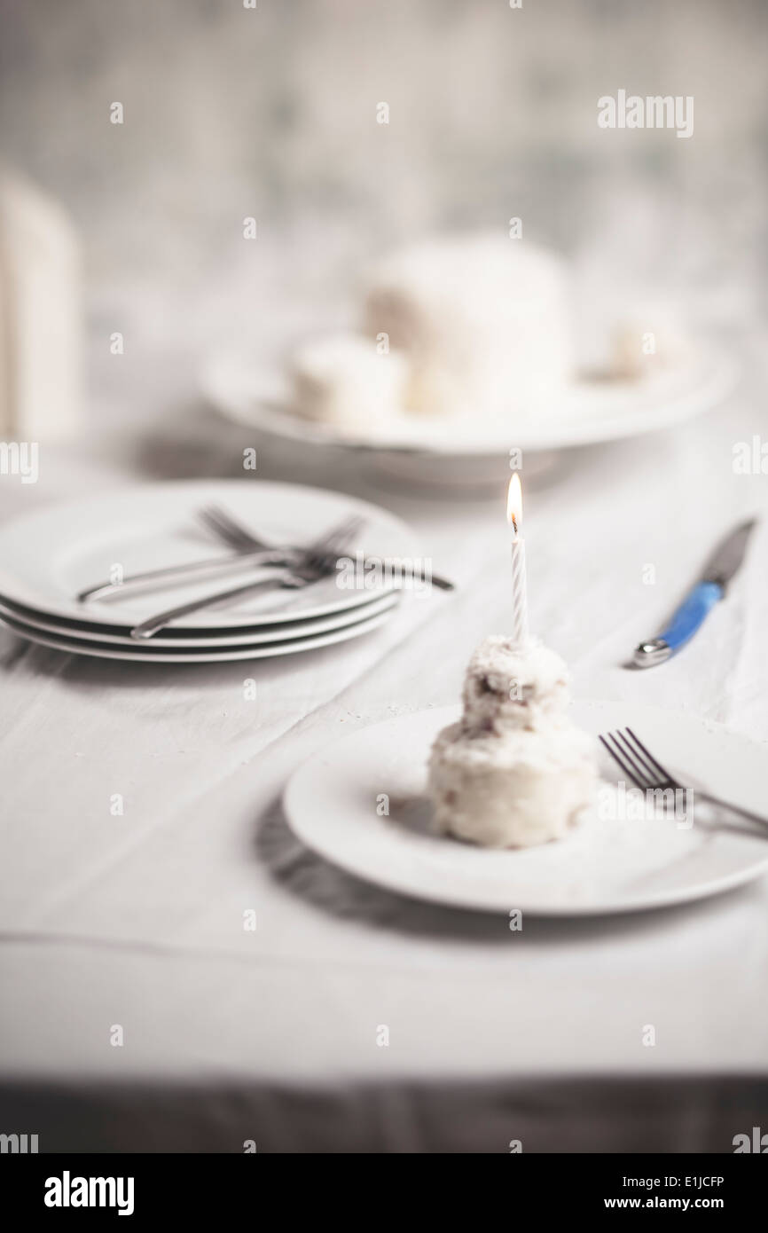 Mini coconut birthday cake with lighted candle on plate Stock Photo - Alamy