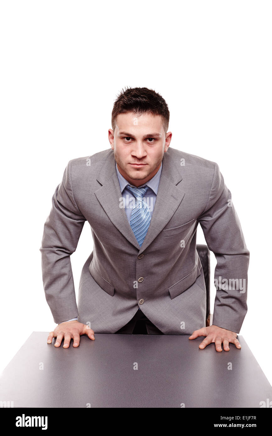 Studio shot of menacing businessman with hands on the desk, isolated ...