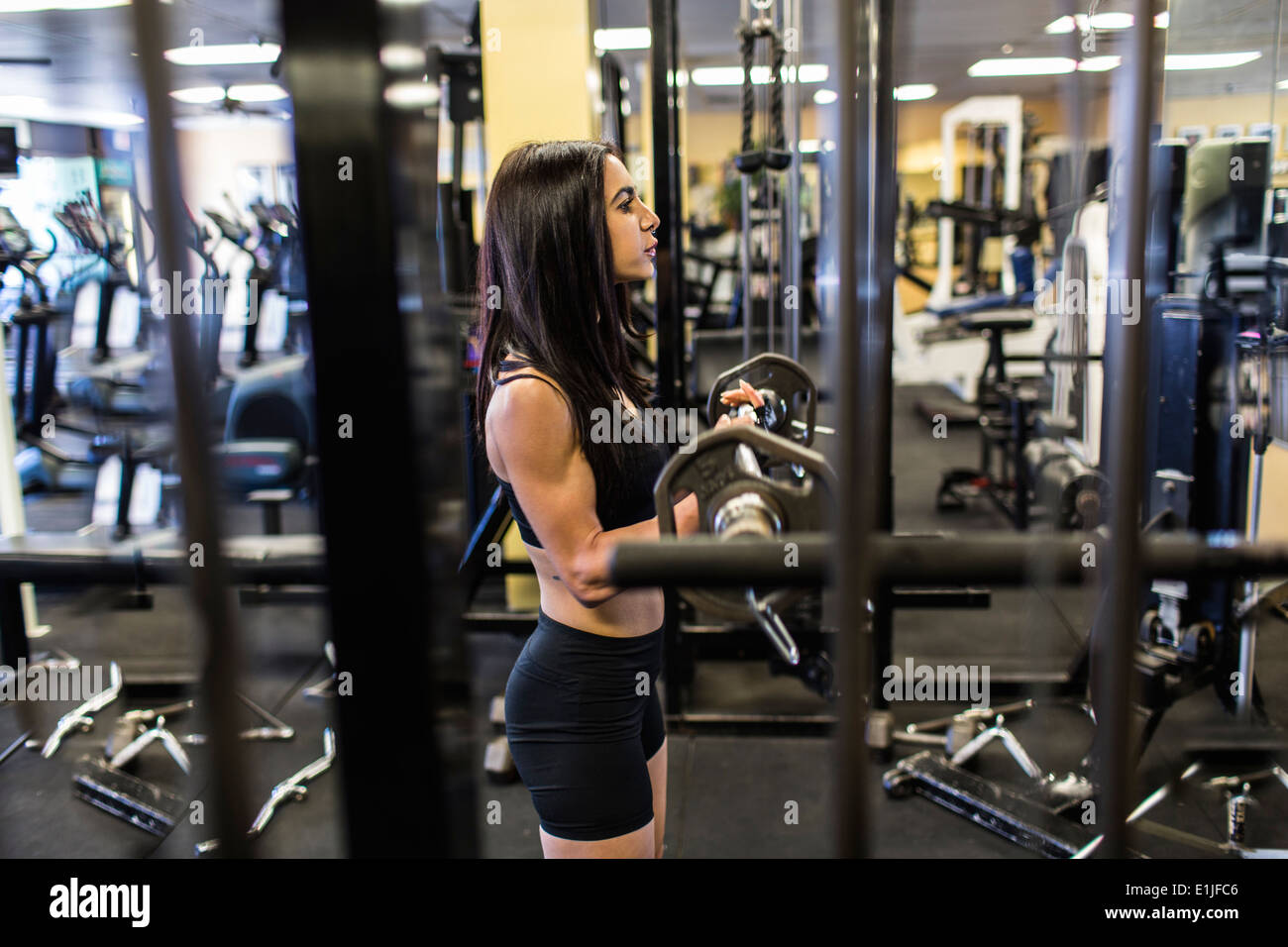 Mid adult woman weightlifting barbell in gym Stock Photo - Alamy