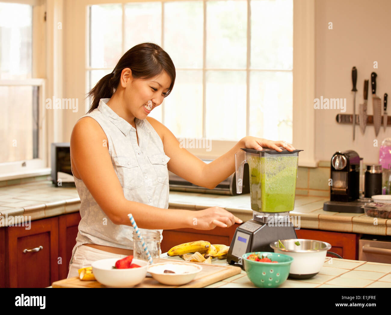 Young woman making green smoothie in kitchen Stock Photo - Alamy