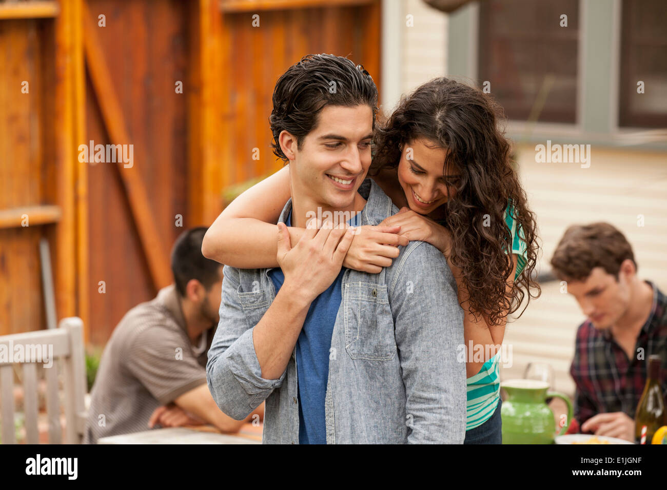 Couple in garden, with arm around, friends in background Stock Photo ...