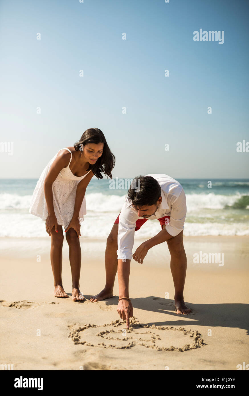 Couple drawing in sand on Arpoador beach, Rio De Janeiro, Brazil Stock ...