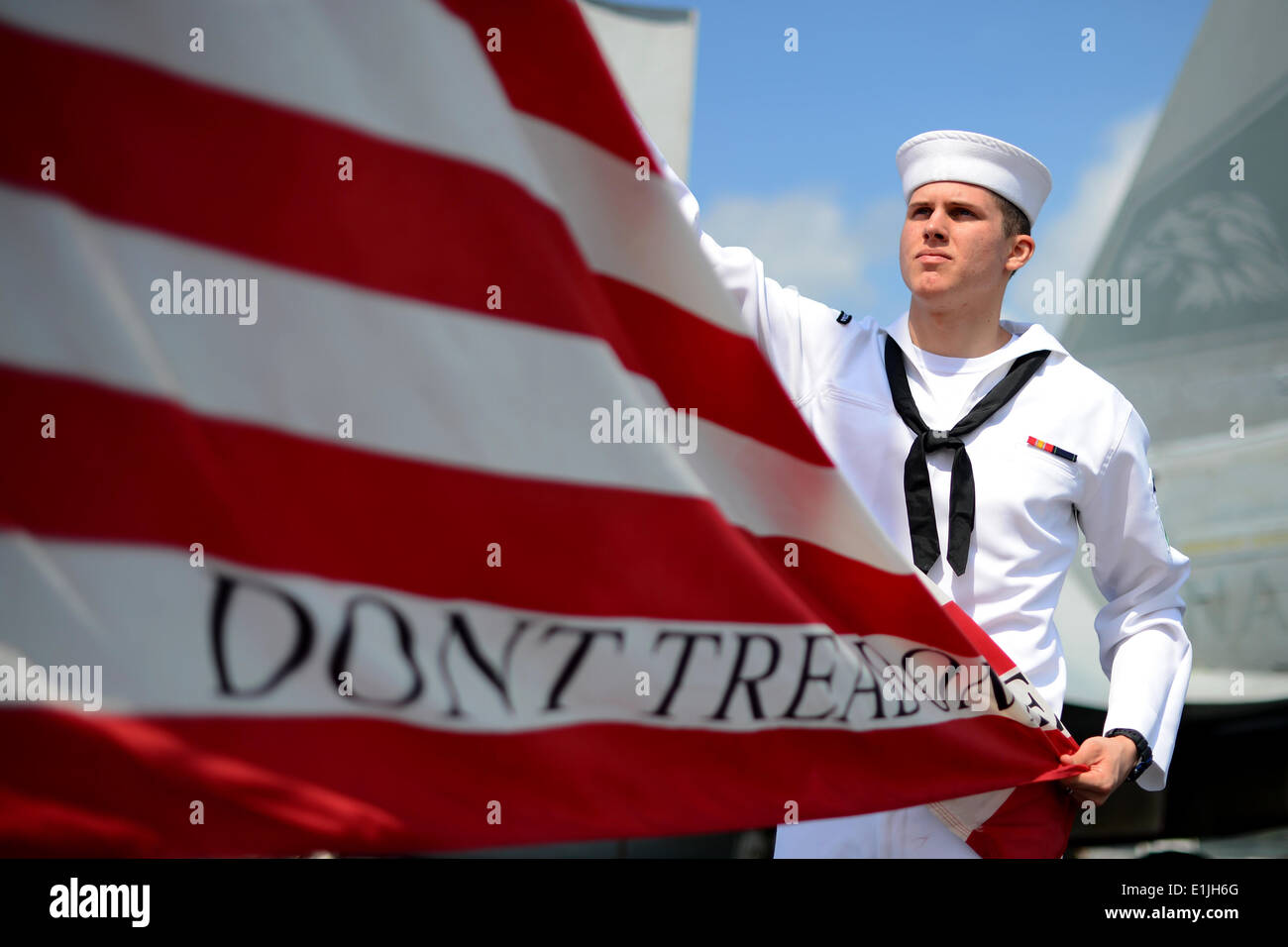 U.S. Navy Airman Justin Frisbie hoists the Navy jack on the flight deck ...