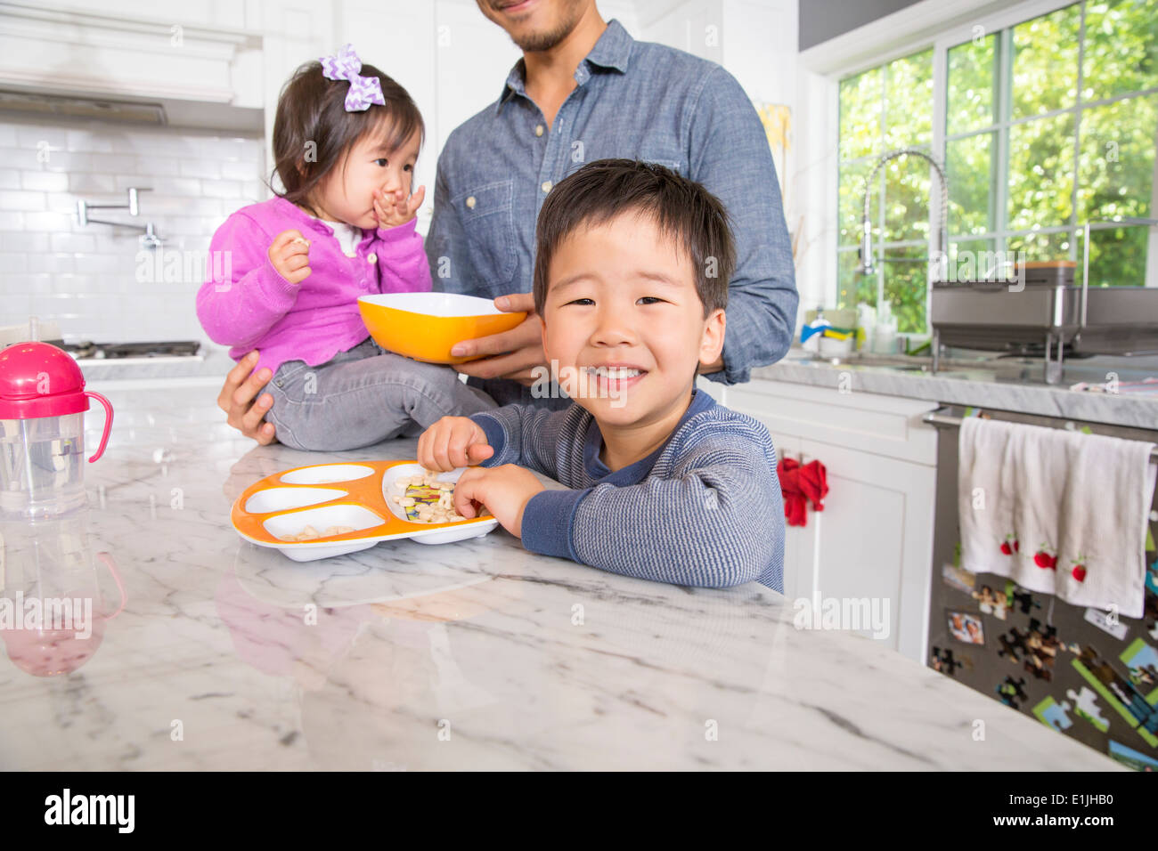 Mid adult man with two young children snacking in kitchen Stock Photo ...