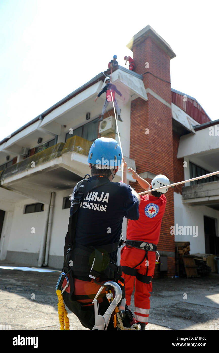 A Macedonian first responder team rescues a man from a building during ...