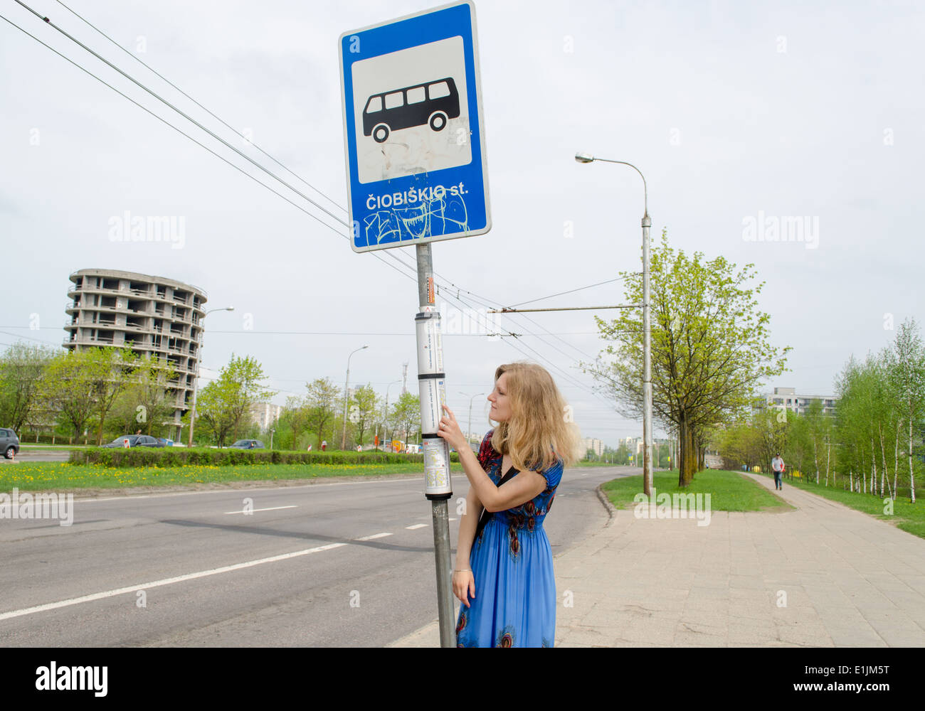 young blonde woman at the bus stop with bus pole tags driving schedules ...