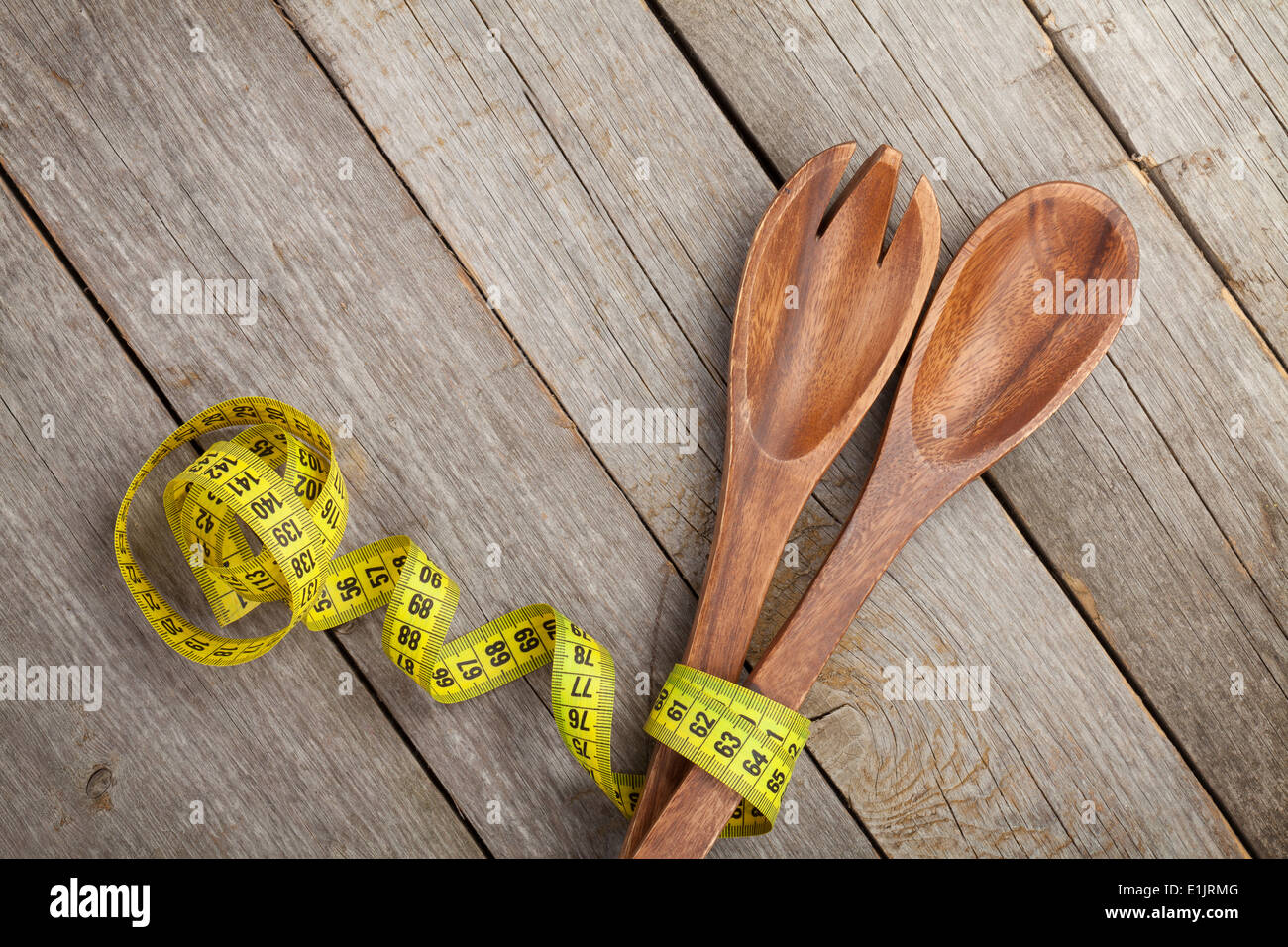 Measure tape with kitchen utensils. Diet food on wooden table with copy ...
