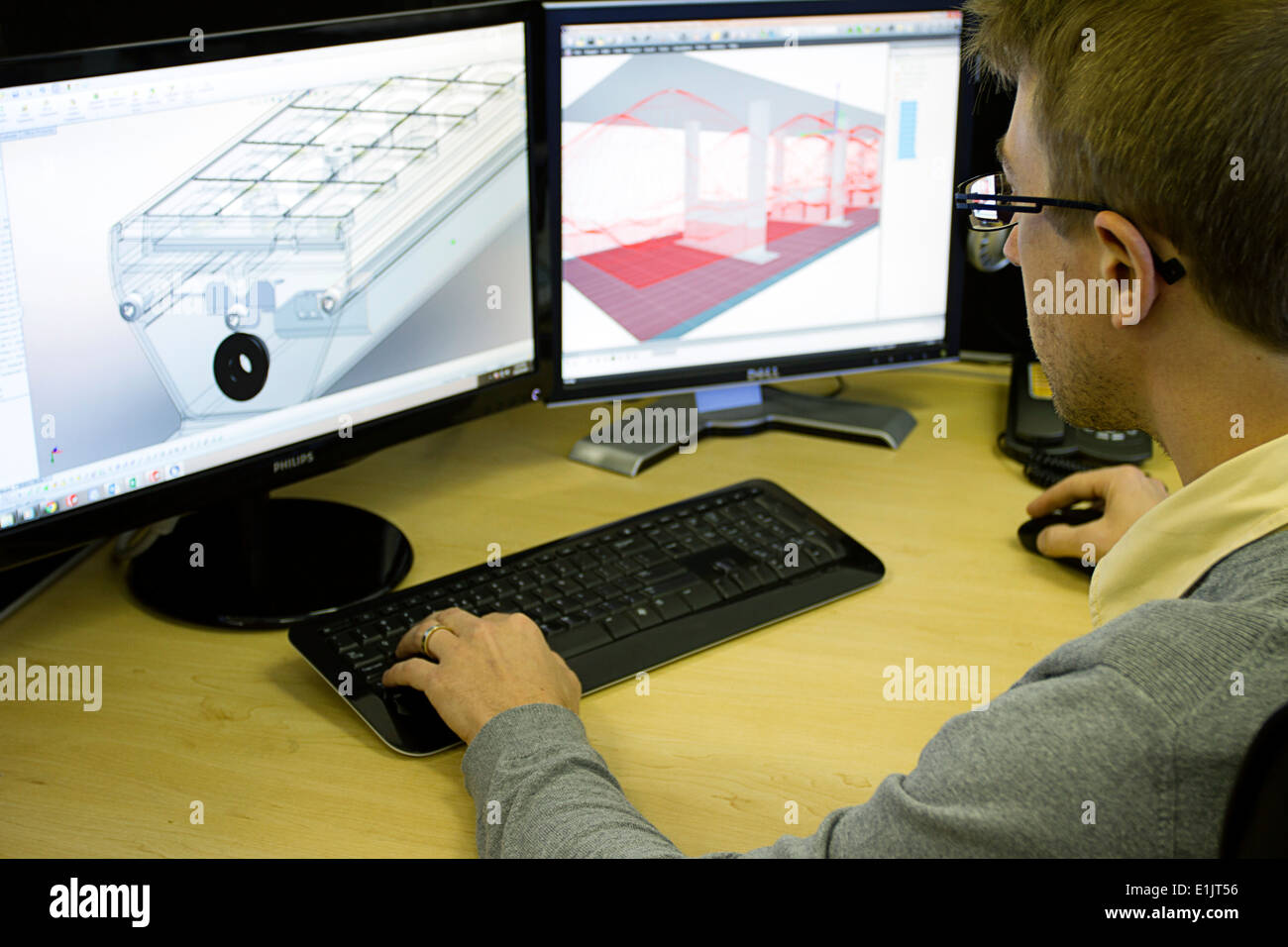 A man working at his desk in front of dual flat screen monitors Stock ...