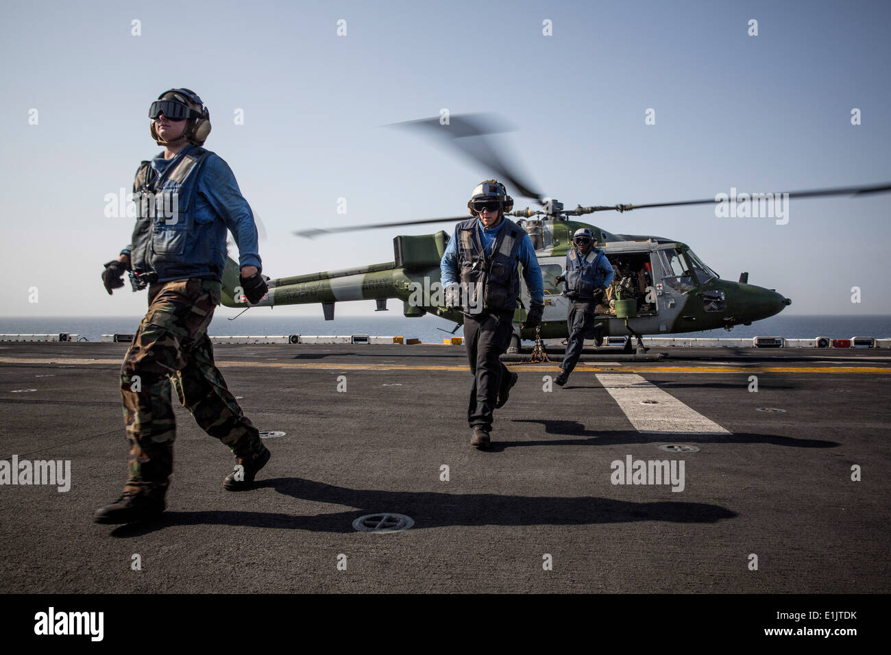 U.S. Sailors run after securing a British Royal Navy Lynx MK 8 ...