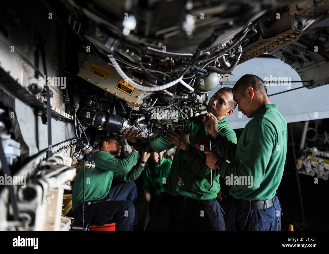 U.S. Sailors assigned to Strike Fighter Squadron (VFA) 147 perform maintenance on an F/A-18E ...