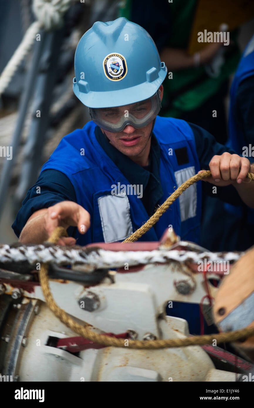 U.S. Navy Seaman Thomas Tolbert uses a line to secure the fueling probe ...
