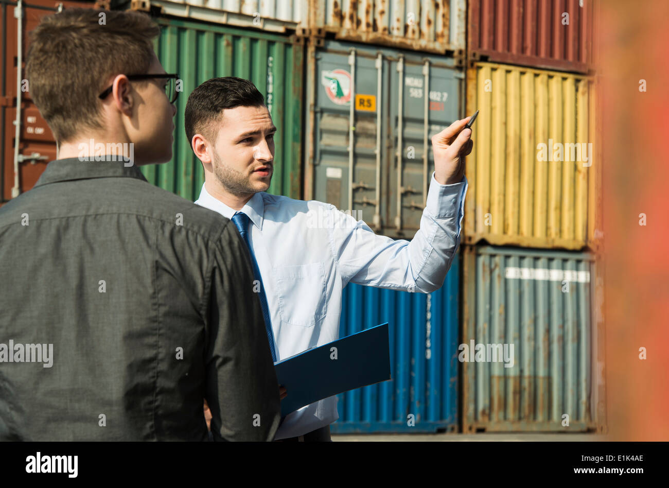Businessman talking to teenager at container terminal Stock Photo - Alamy