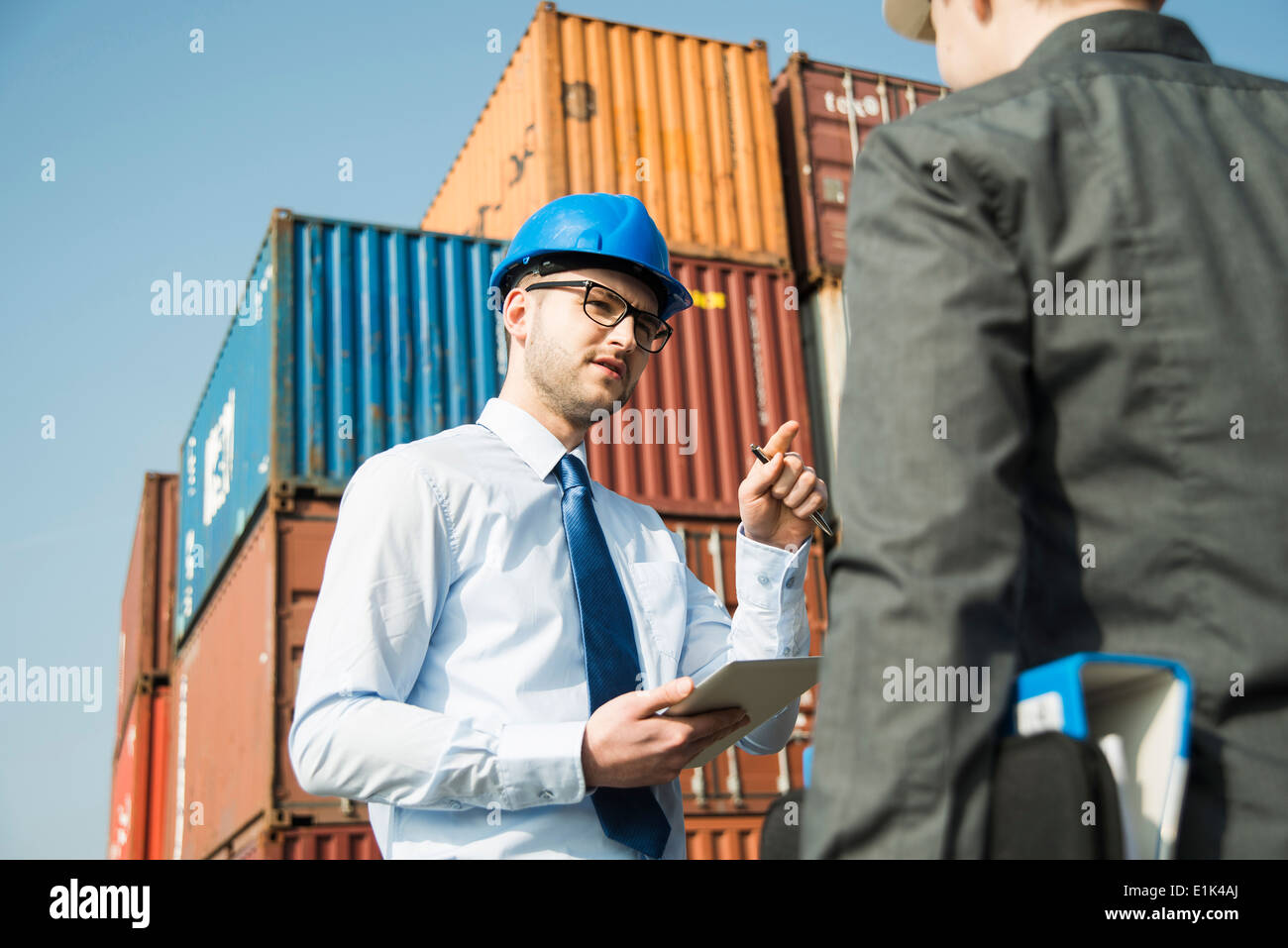 Businessman talking to teenager at container terminal Stock Photo - Alamy