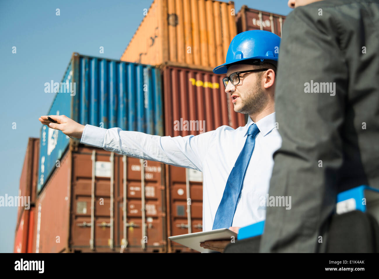Businessman talking to teenager at container terminal Stock Photo - Alamy