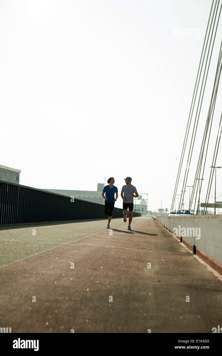 Young man and teenager running on bridge Stock Photo - Alamy