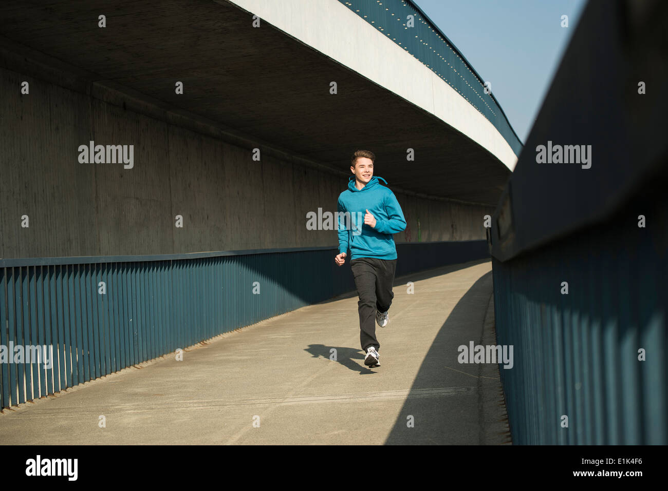 Young man running on bridge Stock Photo - Alamy