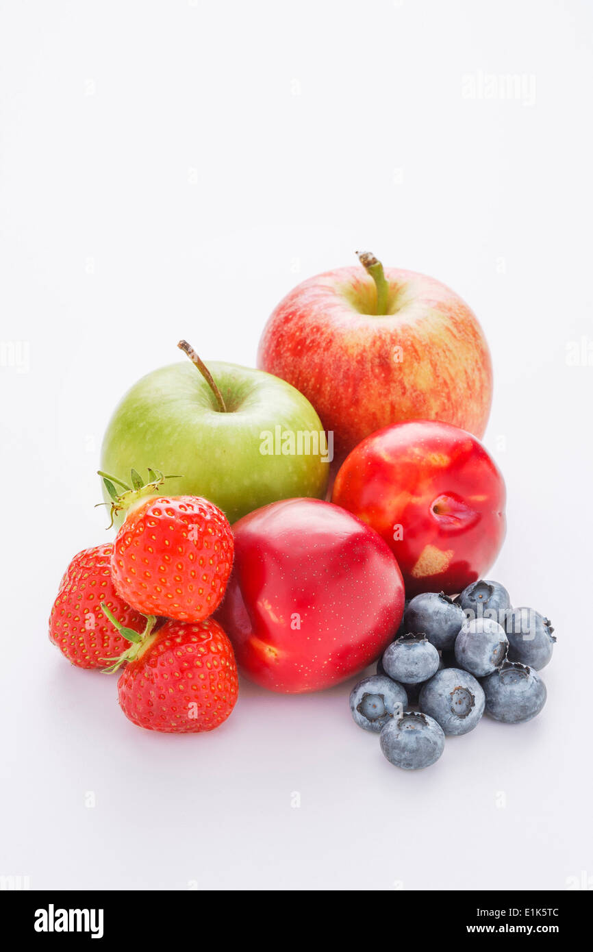 A selection of mixed fruit on a white background These include apples ...