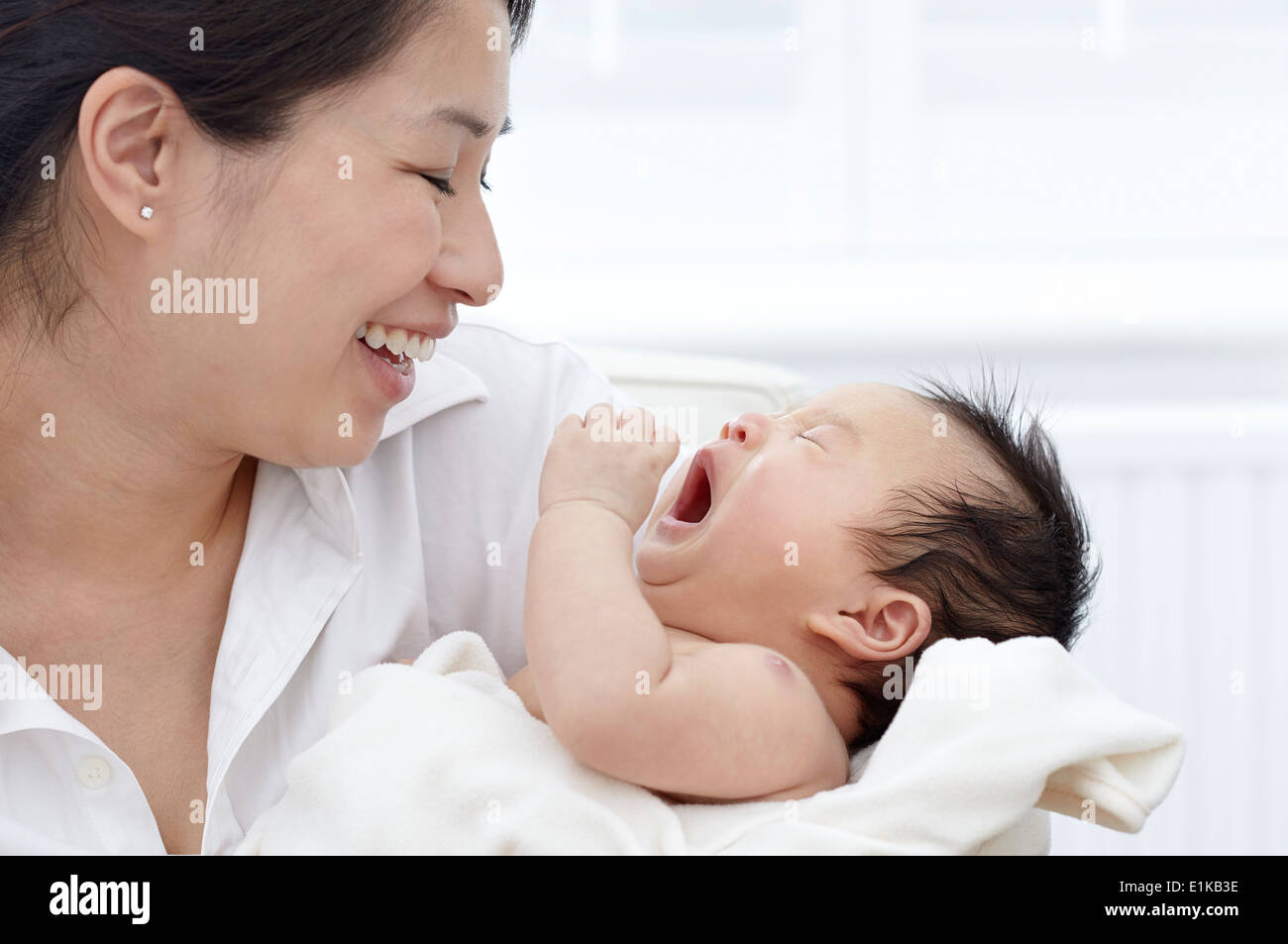 MODEL RELEASED Mother smiling and holding baby girl yawning Stock Photo ...
