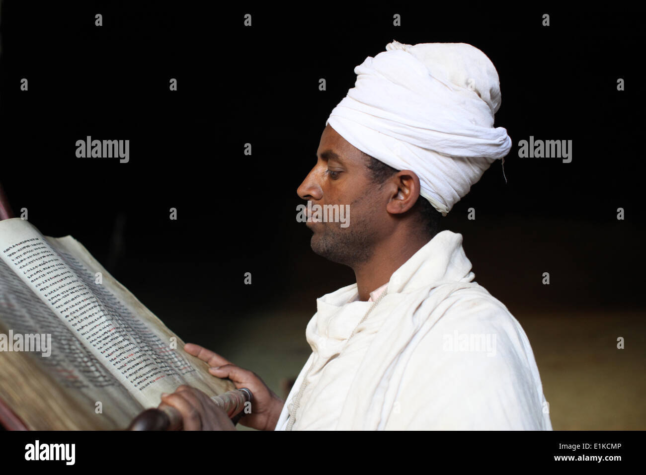 Priest reading a Bible at St. Yimrhane Kristos cave church Stock Photo ...