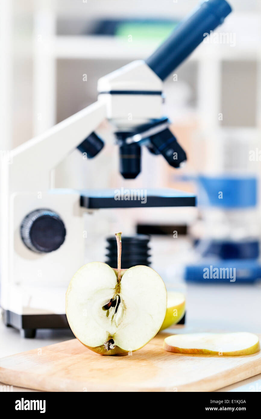 Microscope with half an apple in the foreground Stock Photo - Alamy