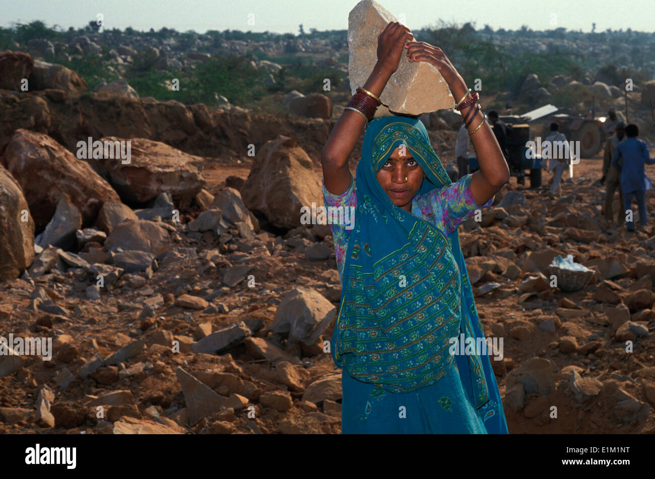 Quarry worker carrying a boulder on her head Stock Photo - Alamy