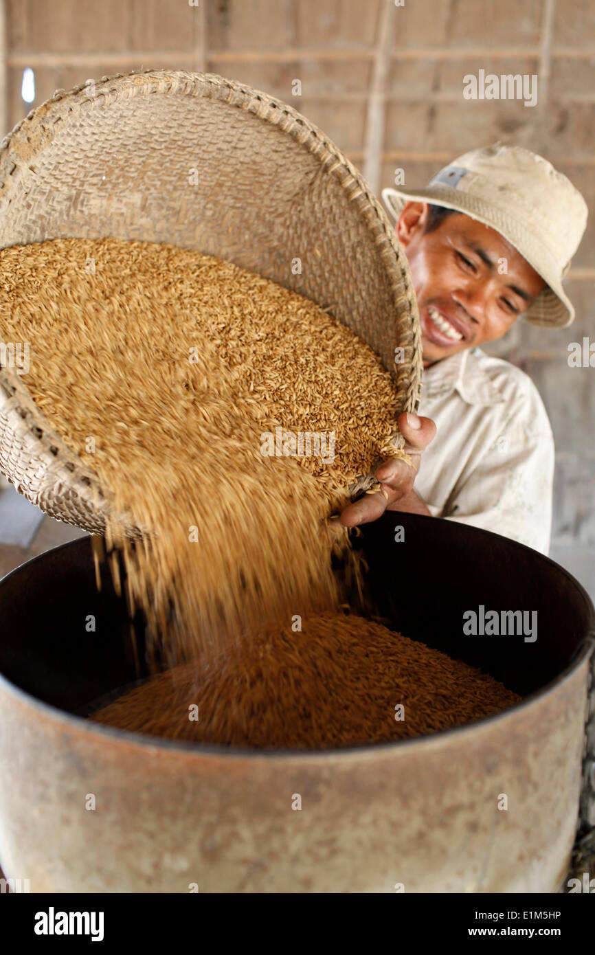 Farmer using a rice husking machine with a loan from HKL microfinance ...
