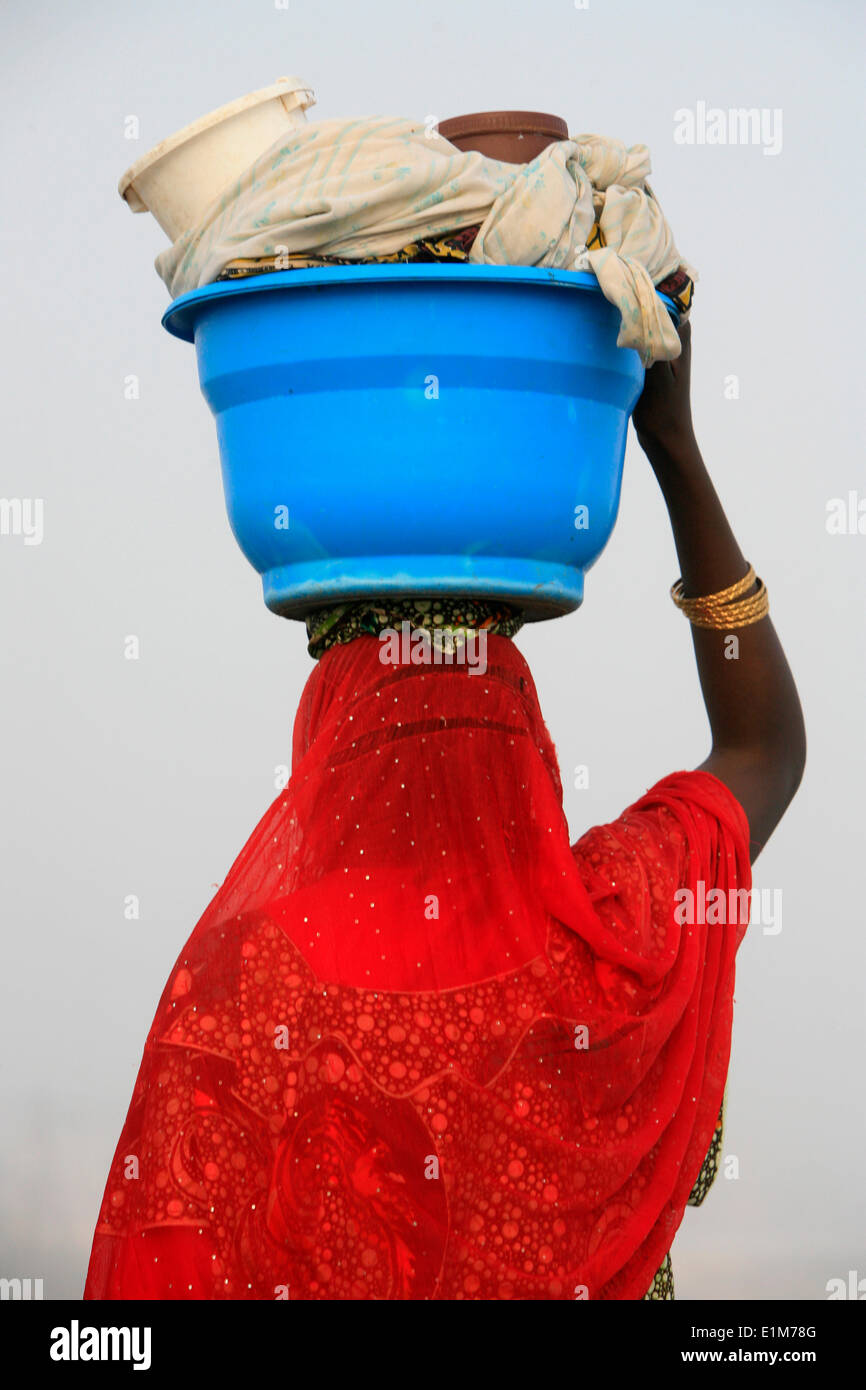 Woman carrying a bucket on her head Stock Photo - Alamy
