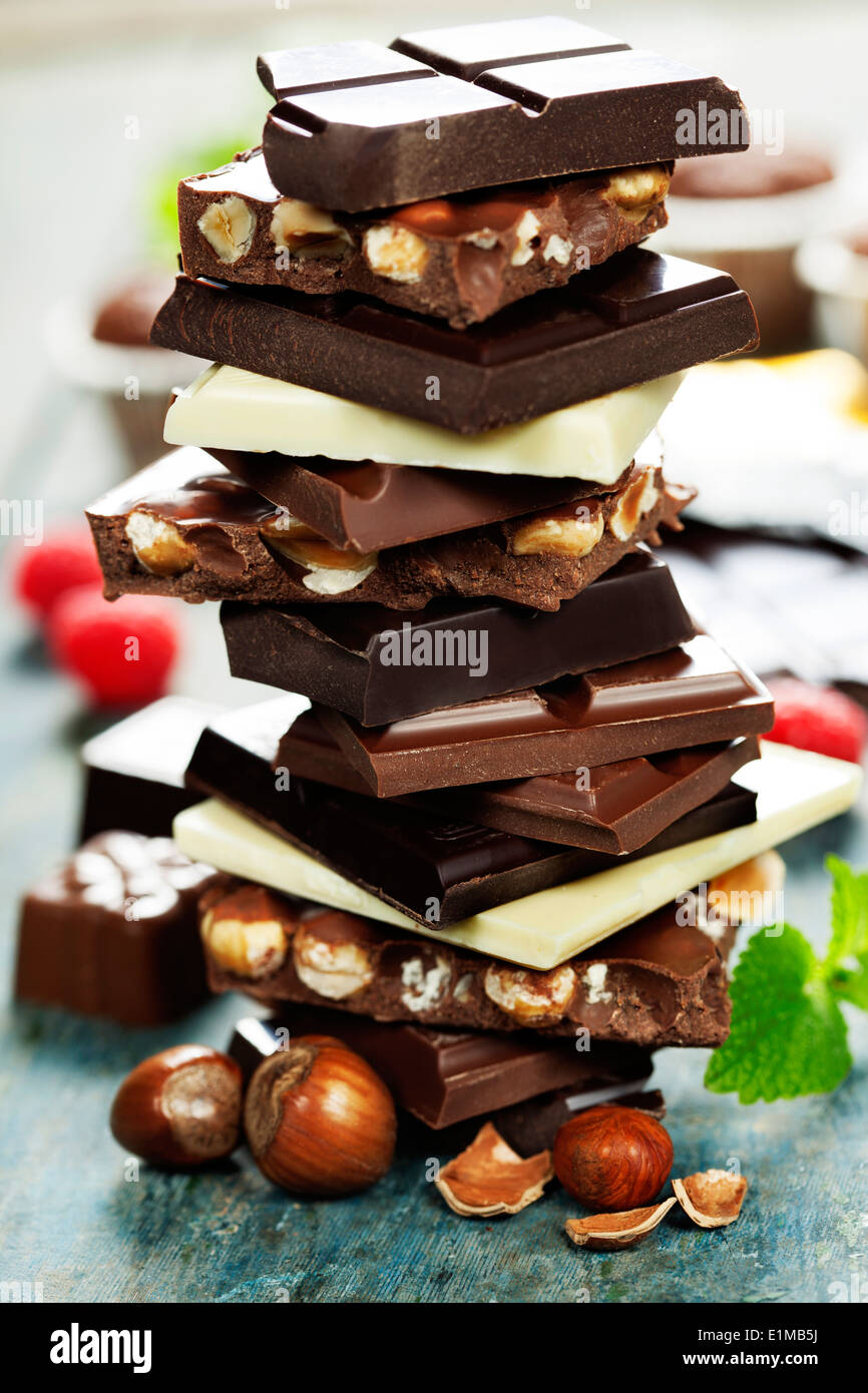 An assortment of white, dark, and milk chocolate with nuts on wooden ...