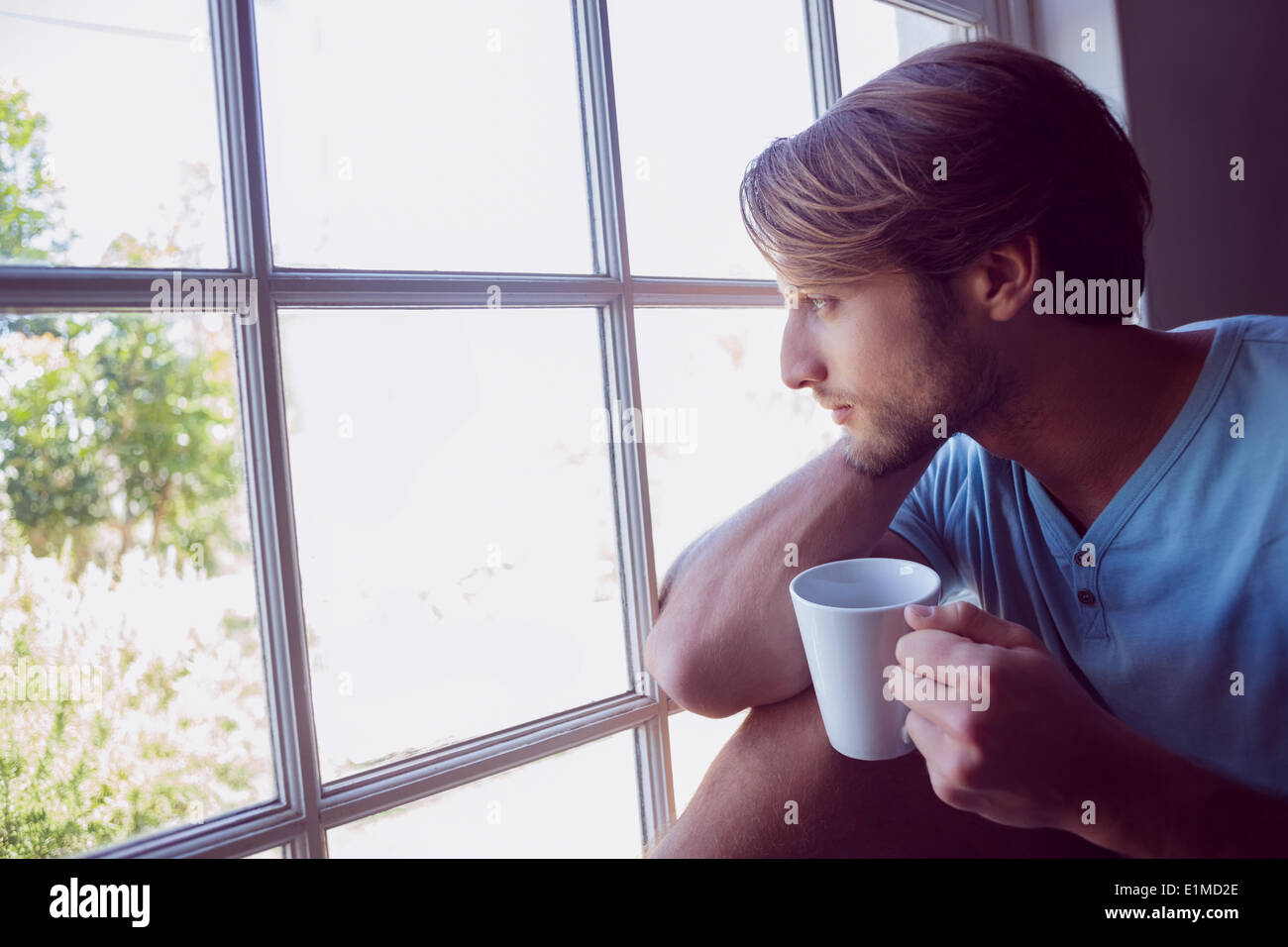 Thoughtful man sitting by the window having coffee Stock Photo - Alamy
