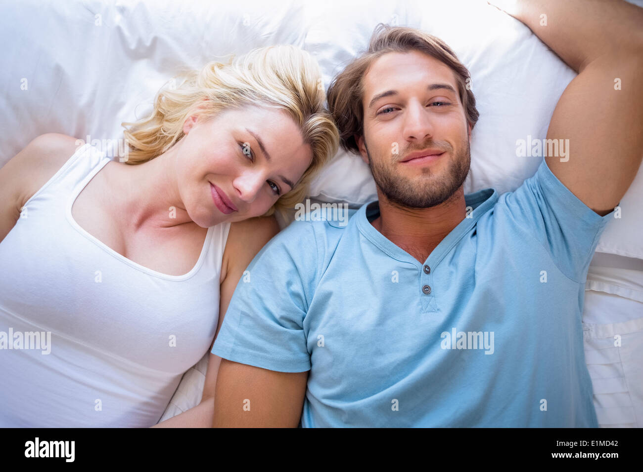 Cute couple relaxing on bed smiling at camera Stock Photo - Alamy