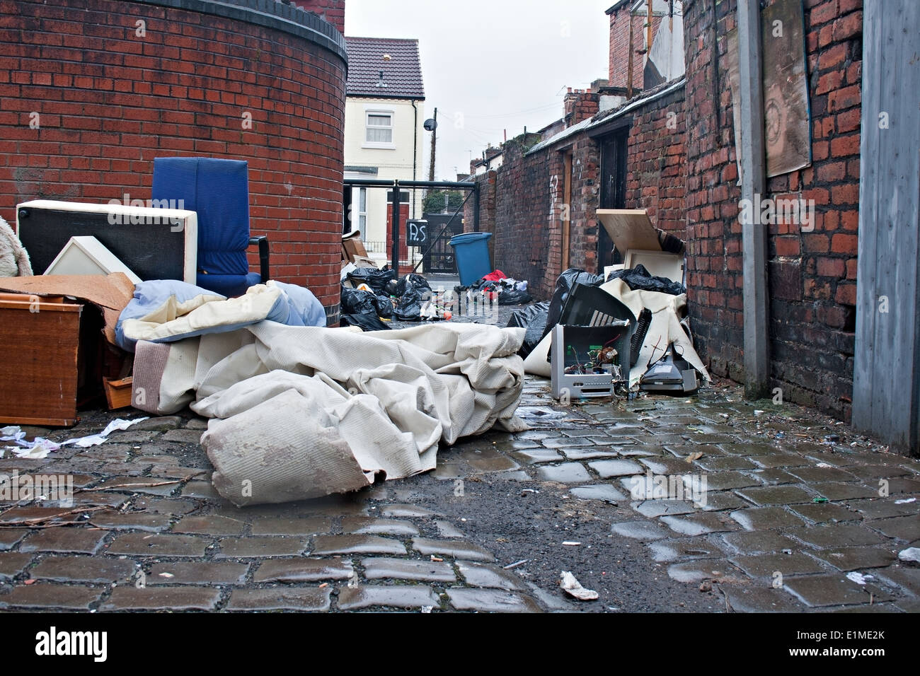 Household rubbish left lying about in a dirty back street cobble stoned ...
