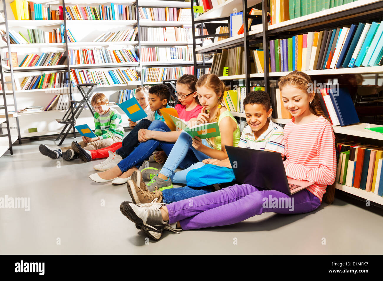 Children sitting on floor in library and studying Stock Photo - Alamy