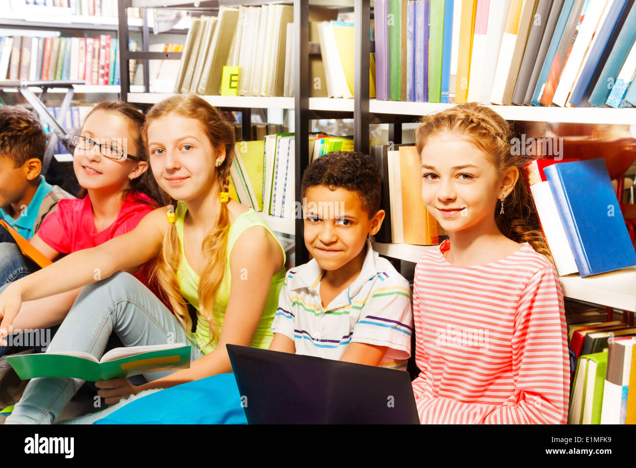 Five smiling children sitting in a row on floor Stock Photo - Alamy
