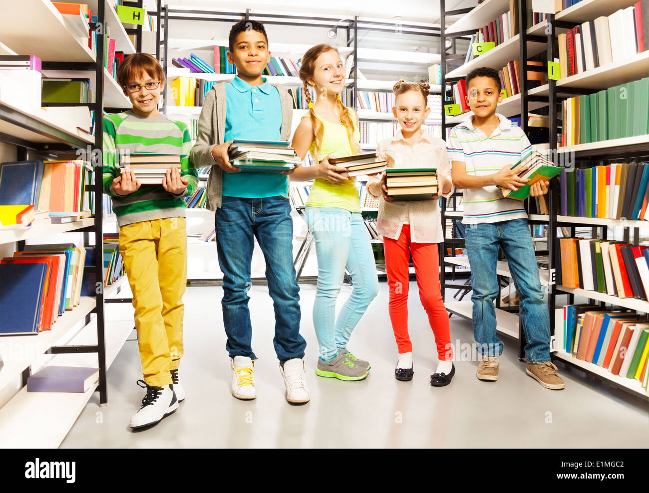 Five friends with piles of books in library Stock Photo - Alamy