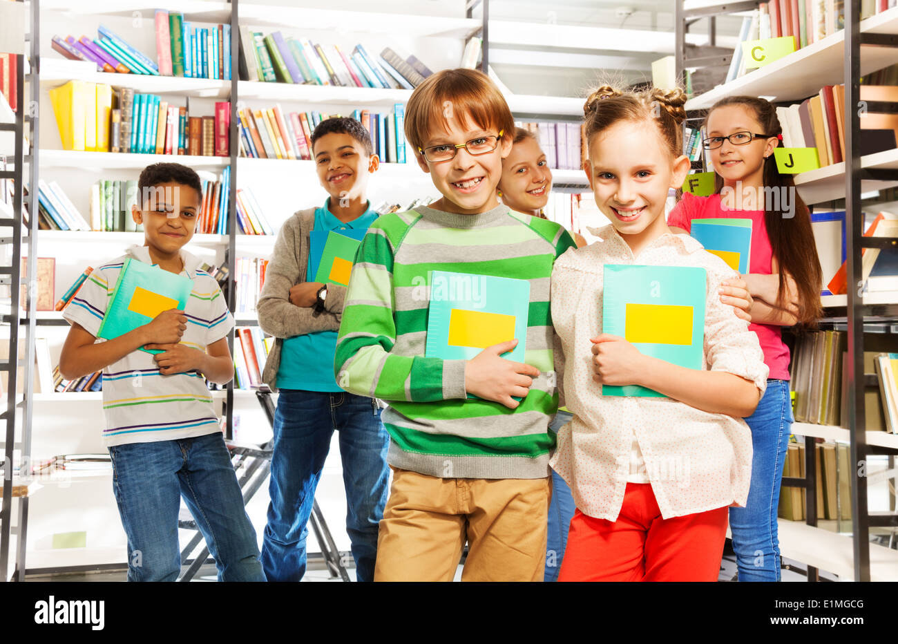 Children in library hold exercise books and stand Stock Photo - Alamy