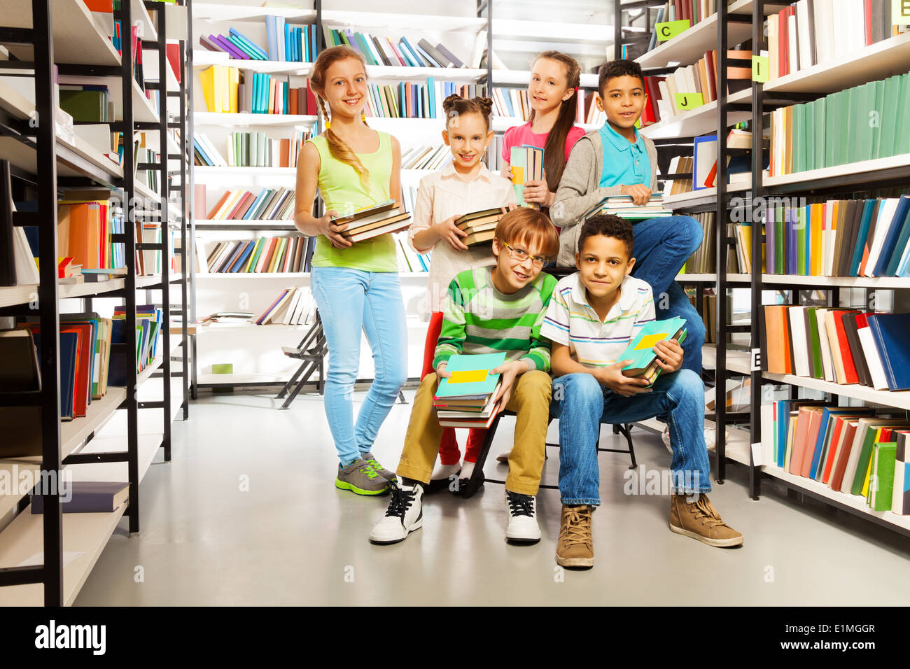 Six pupils in library with piles of books Stock Photo - Alamy