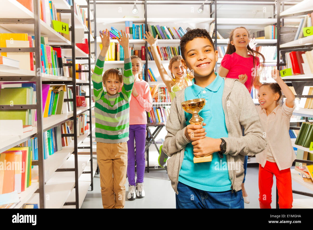 Happy boy holds cup and other kids jumping behind Stock Photo - Alamy