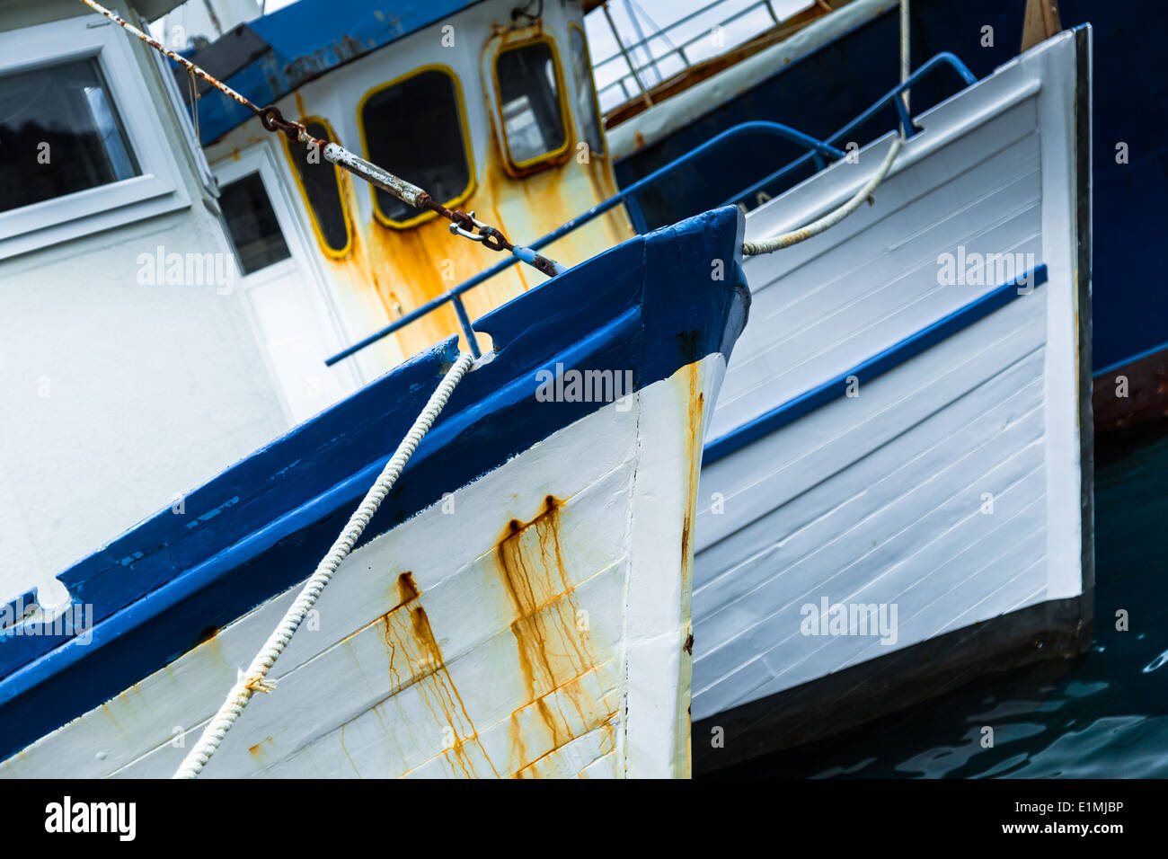 two fishing boats are shown moored with bright white paint and rust ...