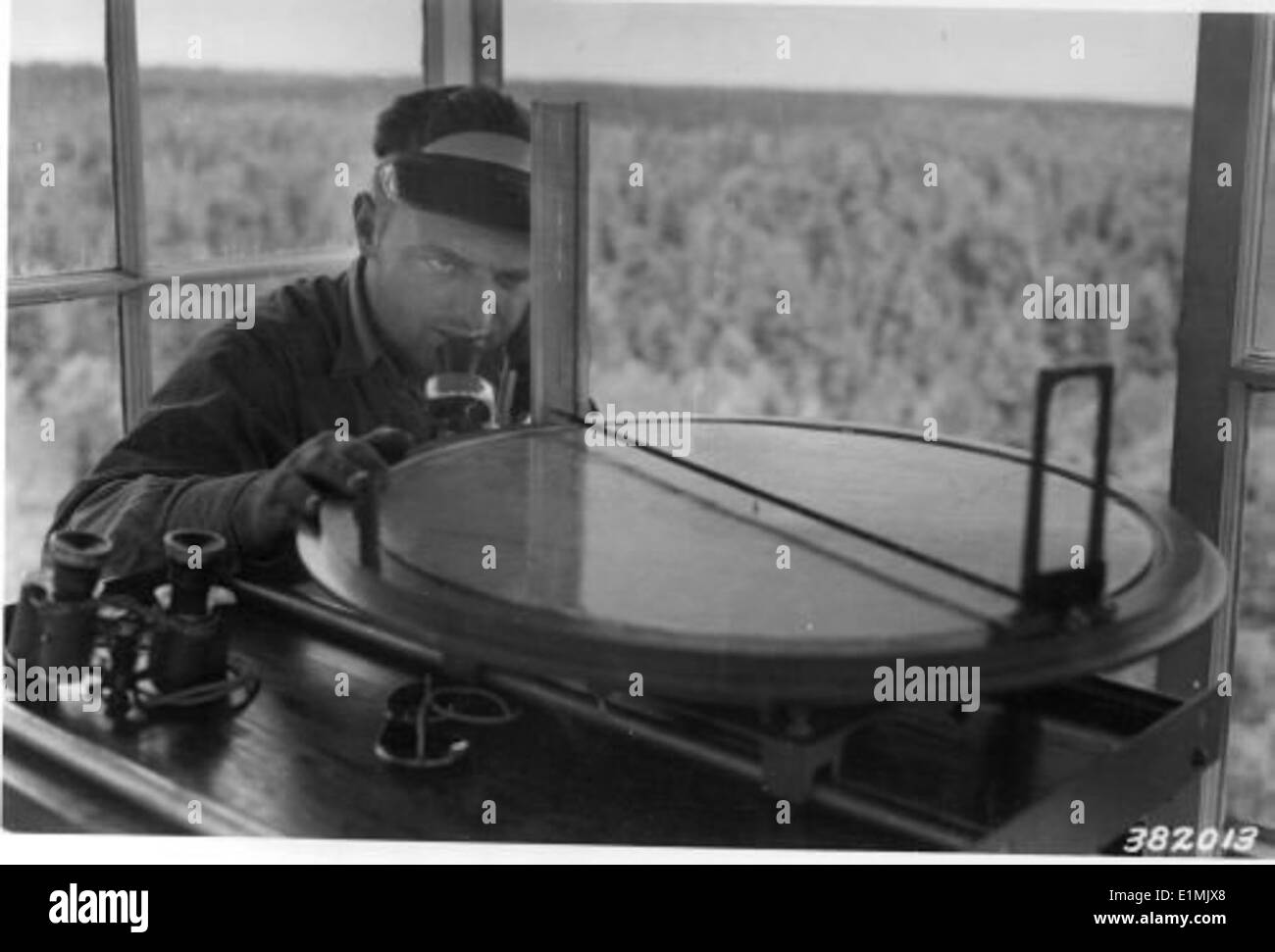 This black and white image shows a fire lookout tower in a forested ...