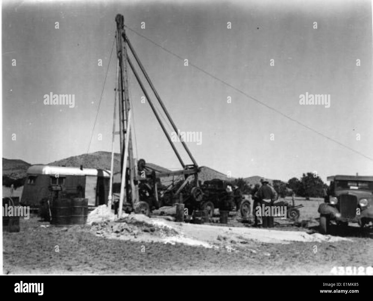 A black-and-white photograph depicting people setting up a water rig at ...